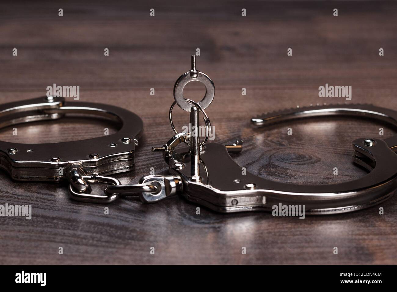 handcuffs and keys on brown wooden table background Stock Photo - Alamy