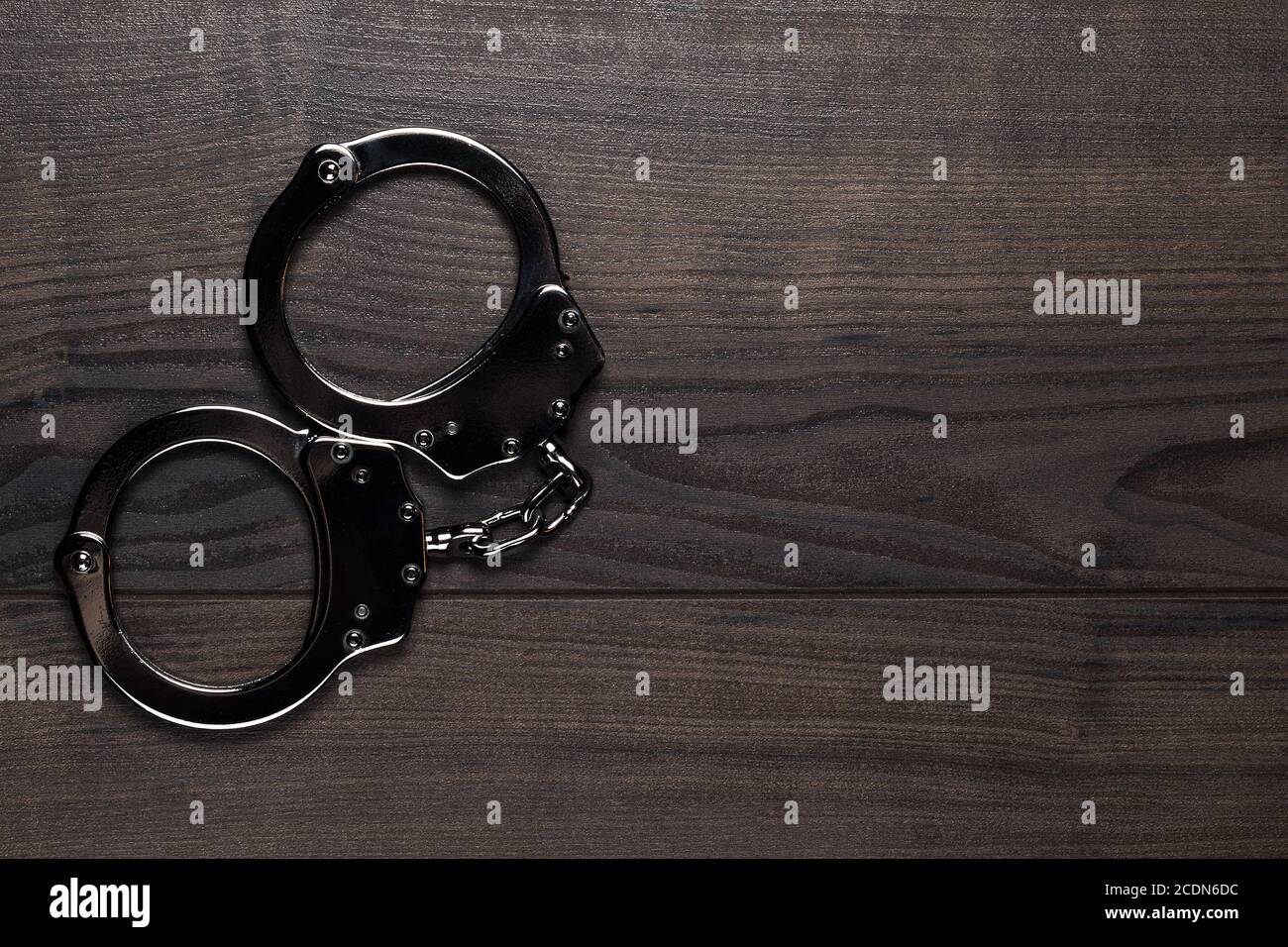 handcuffs on brown wooden table background Stock Photo - Alamy