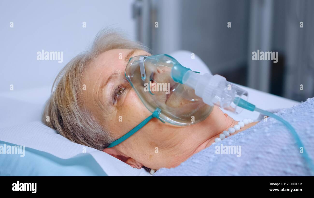 Portrait of retired senior woman breathing slowly with oxygen mask ...