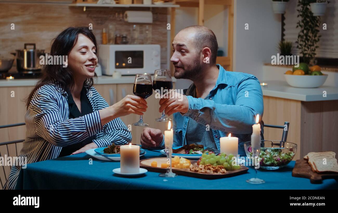 Young married couple enjoying romantic dinner toasting and drinking red ...