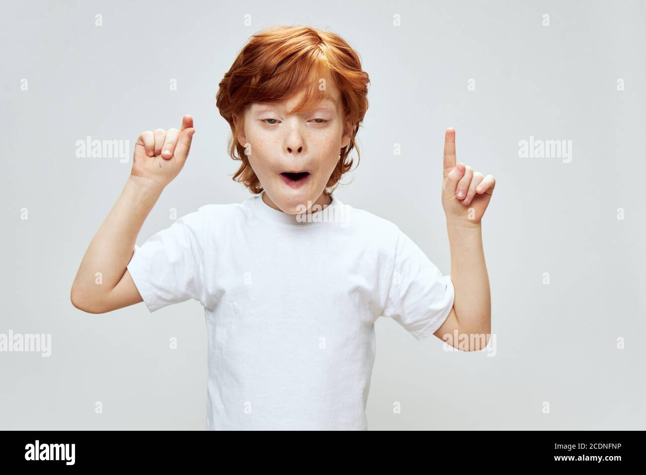 red-haired boy with open mouth and stupid expression on his face shows ...
