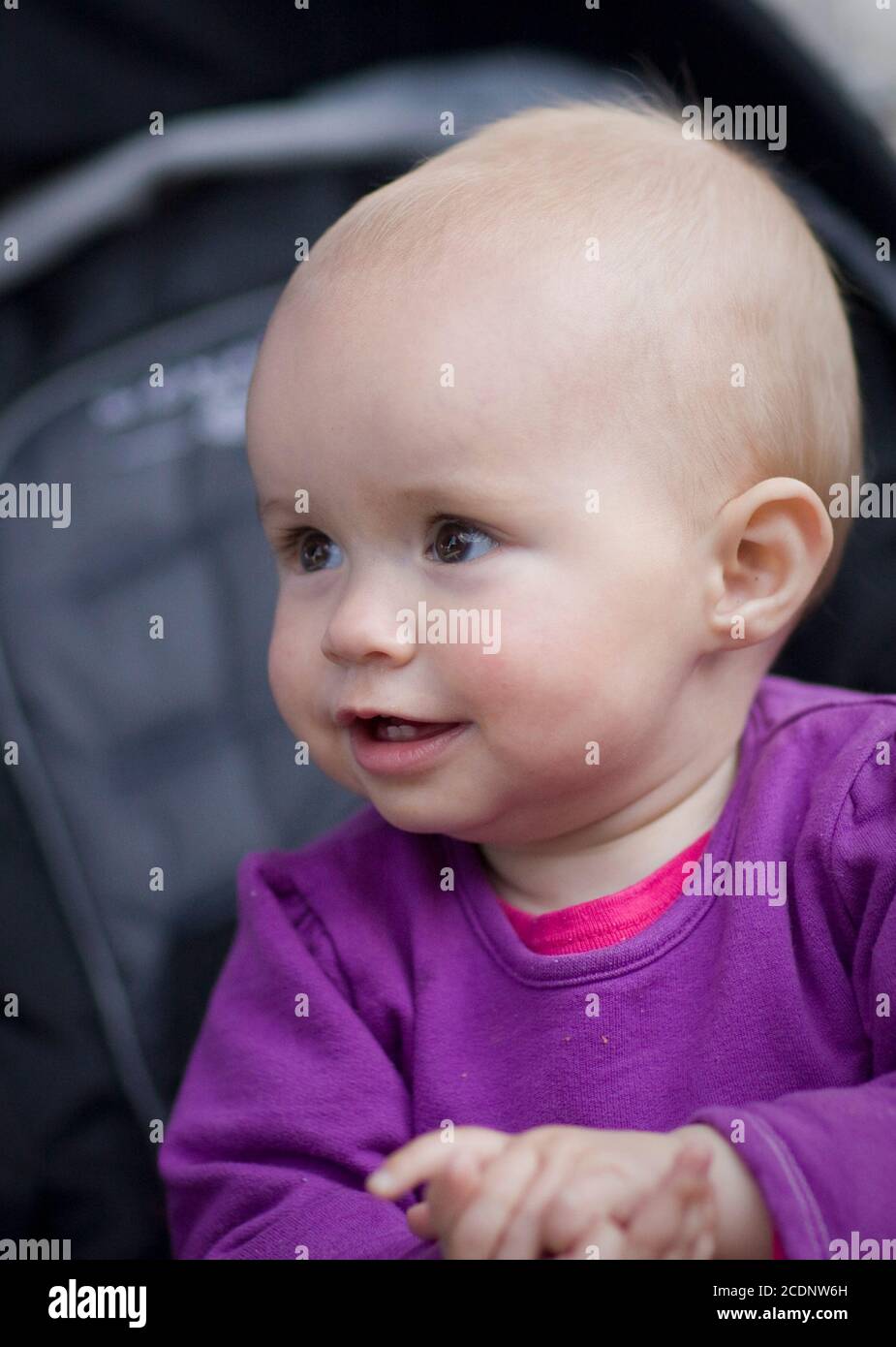 A Happy baby wearing purple clothing, sitting in a stroller Stock Photo ...