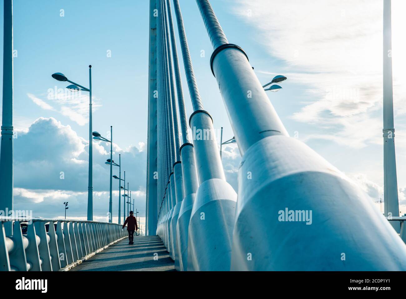 Person walks on an industrial bridge with large pylons and cable ties ...