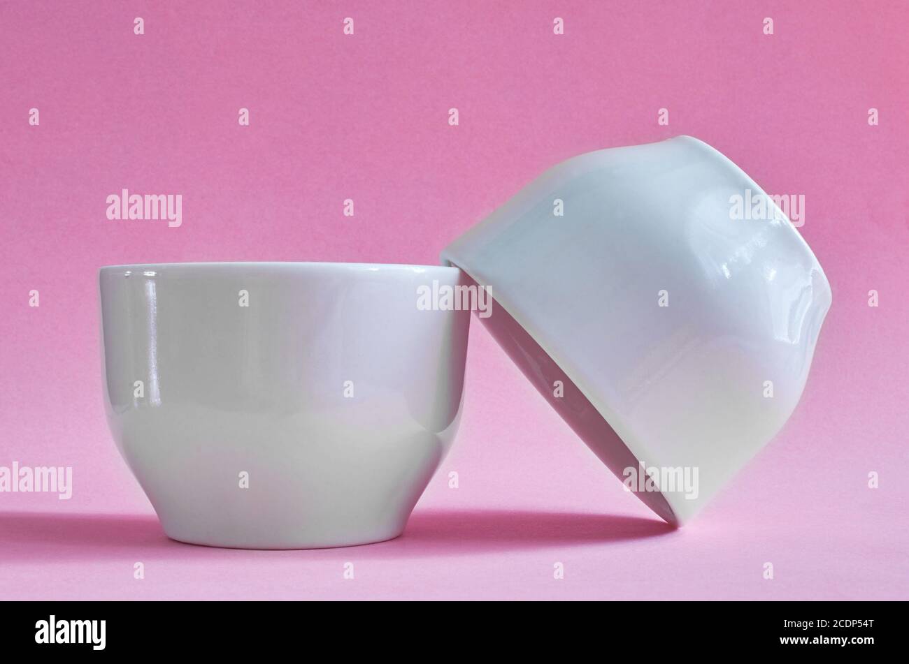 Two white ceramic cups without handles on a pink background Stock Photo ...