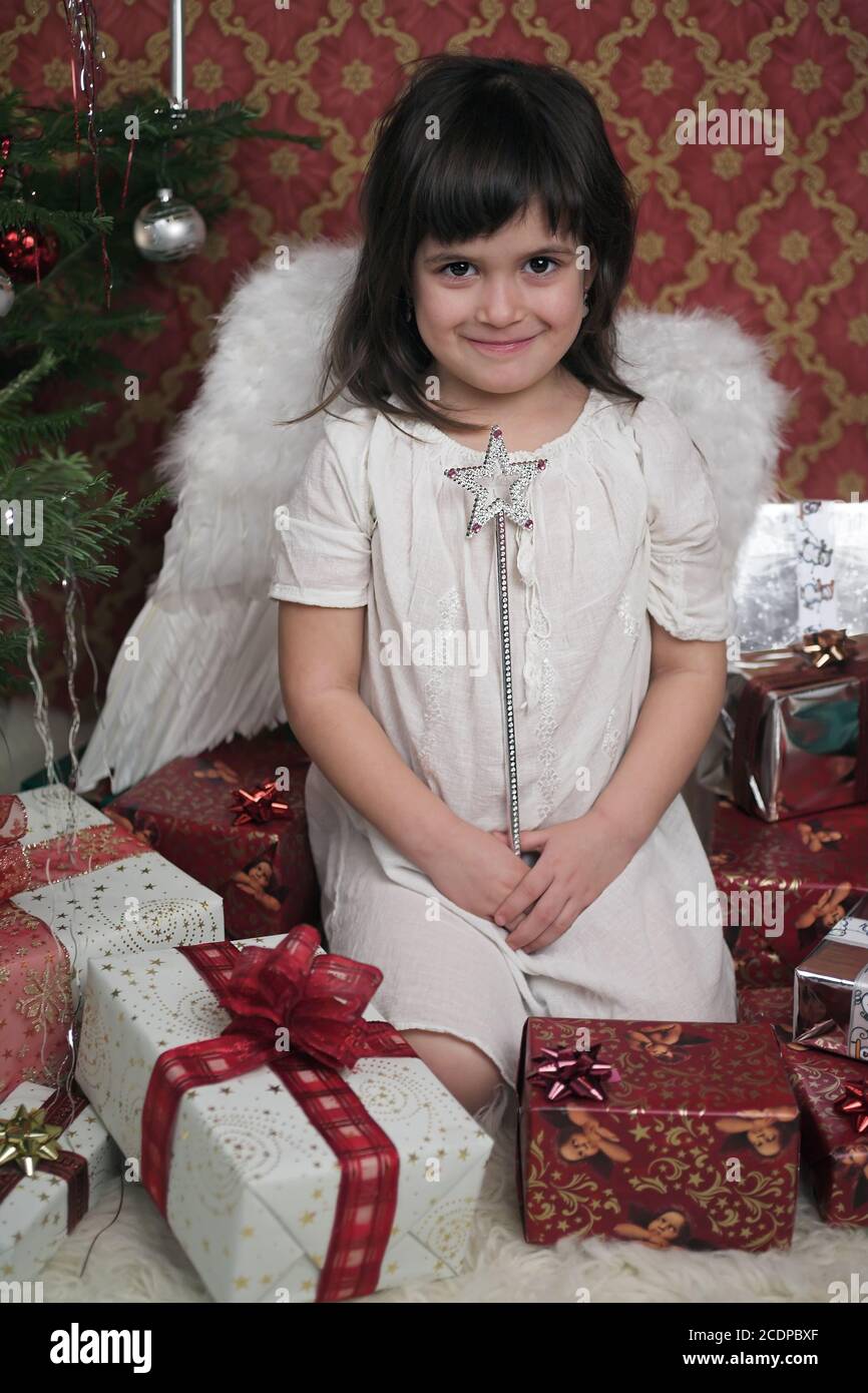 Young girl in christmas setting with angel wings and gift boxes Stock ...