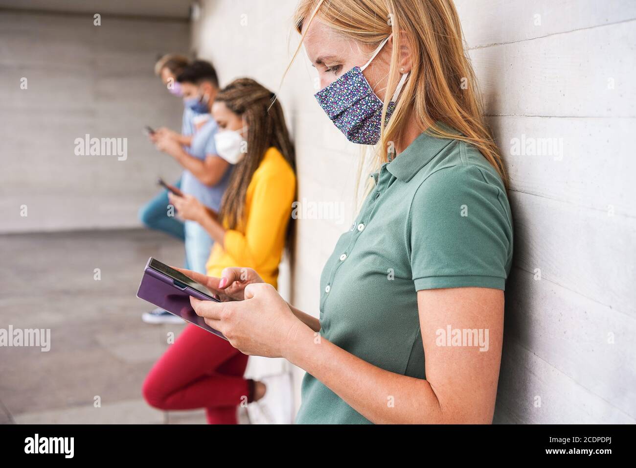 Young people wearing face safety masks using mobile phones while ...