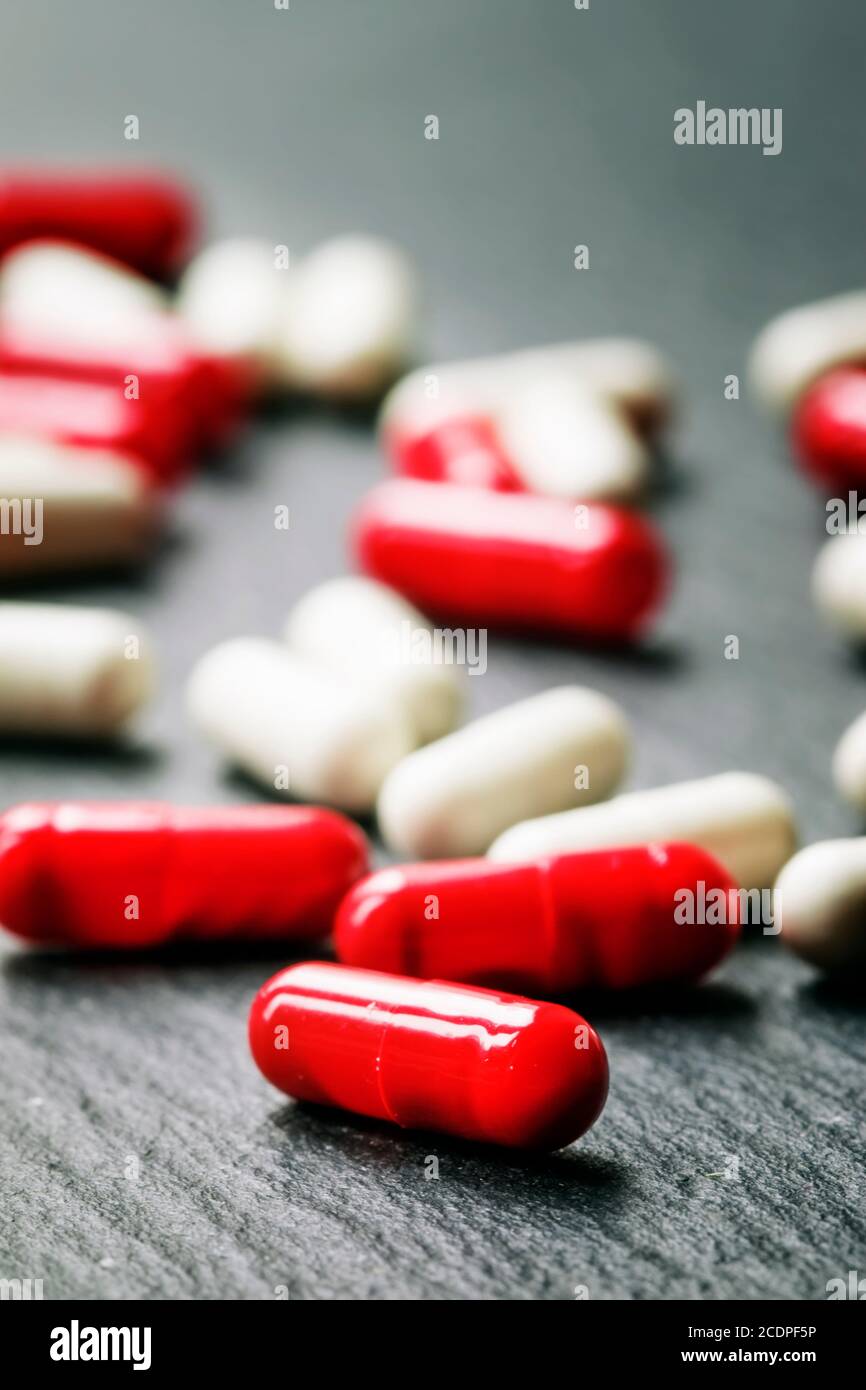 Painkillers pills in red and white capsules on dark background, macro ...
