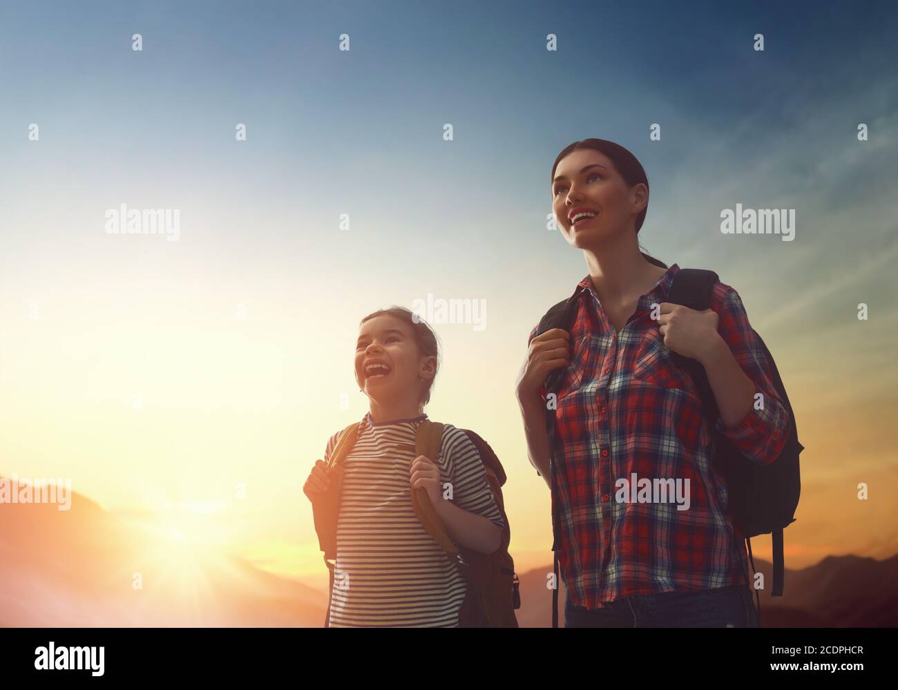 Two travelers at sunset. Mother and child daughter girl are having fun ...