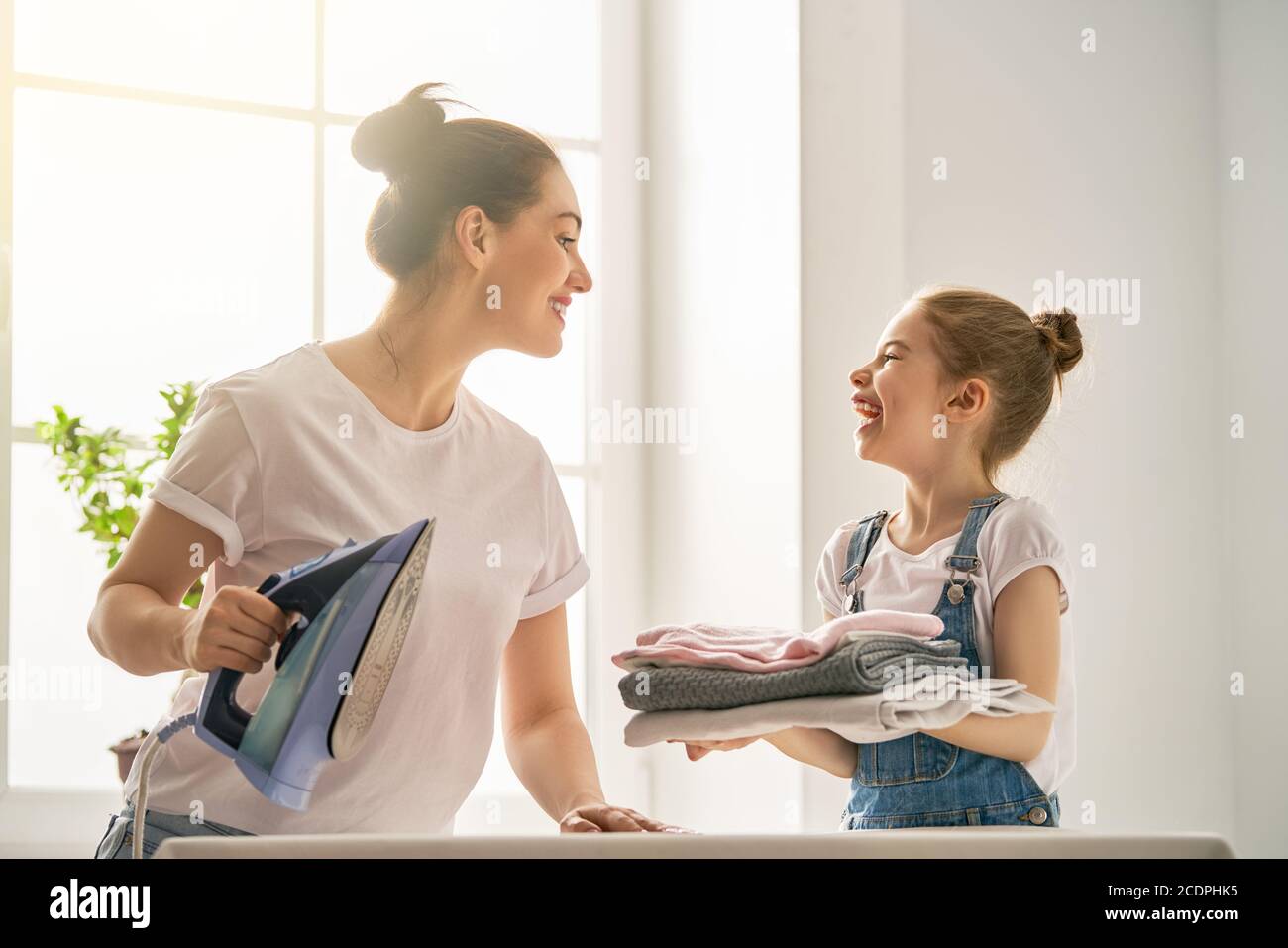 Beautiful young woman and child girl little helper are having fun and ...