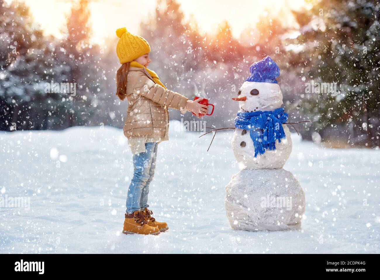 happy child girl plaing with a snowman on a snowy winter walk Stock ...