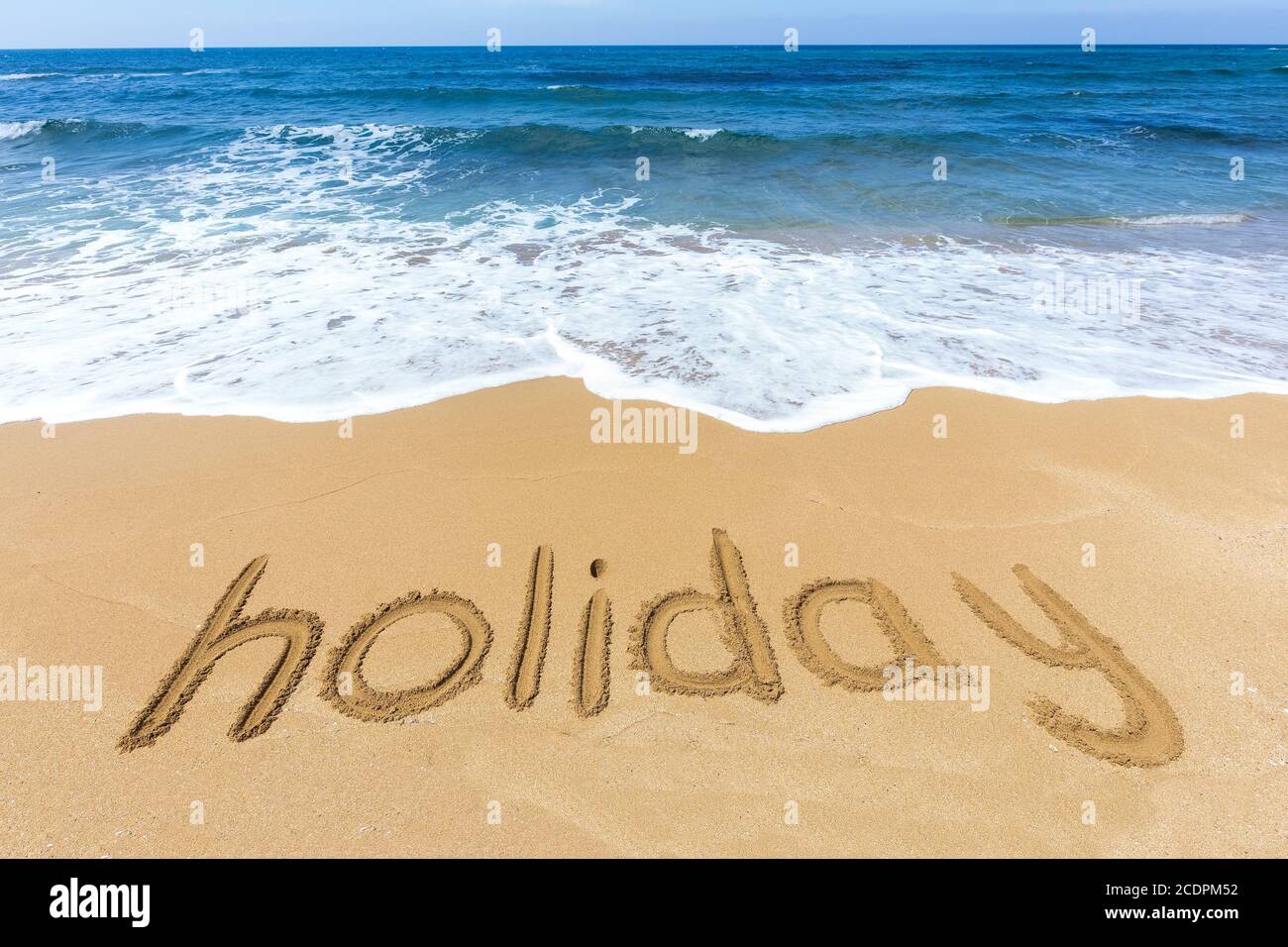 Word holiday written in sand on beach Stock Photo - Alamy