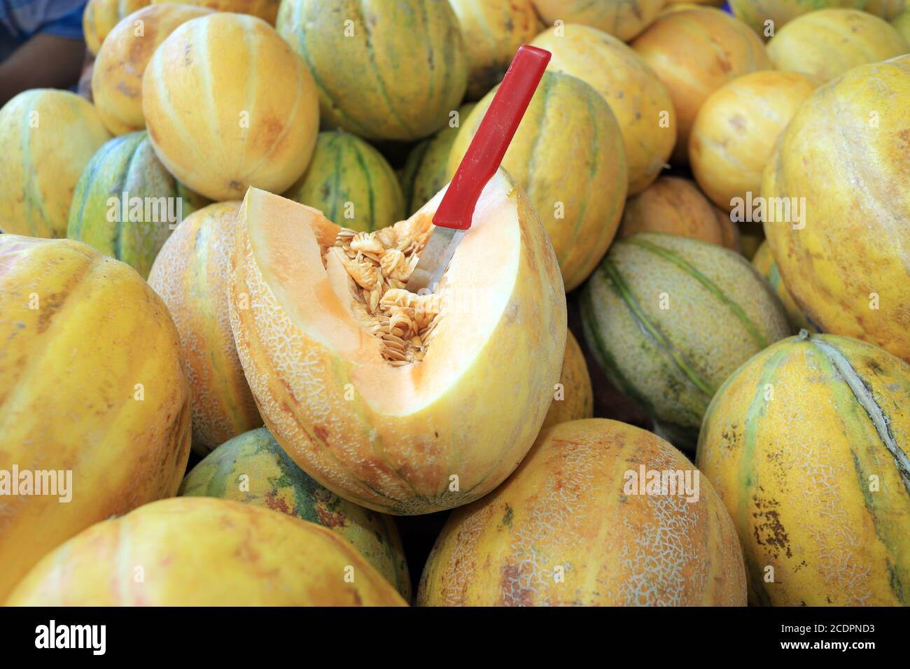 Pile of melons and one melon cut in a half with knife Stock Photo - Alamy