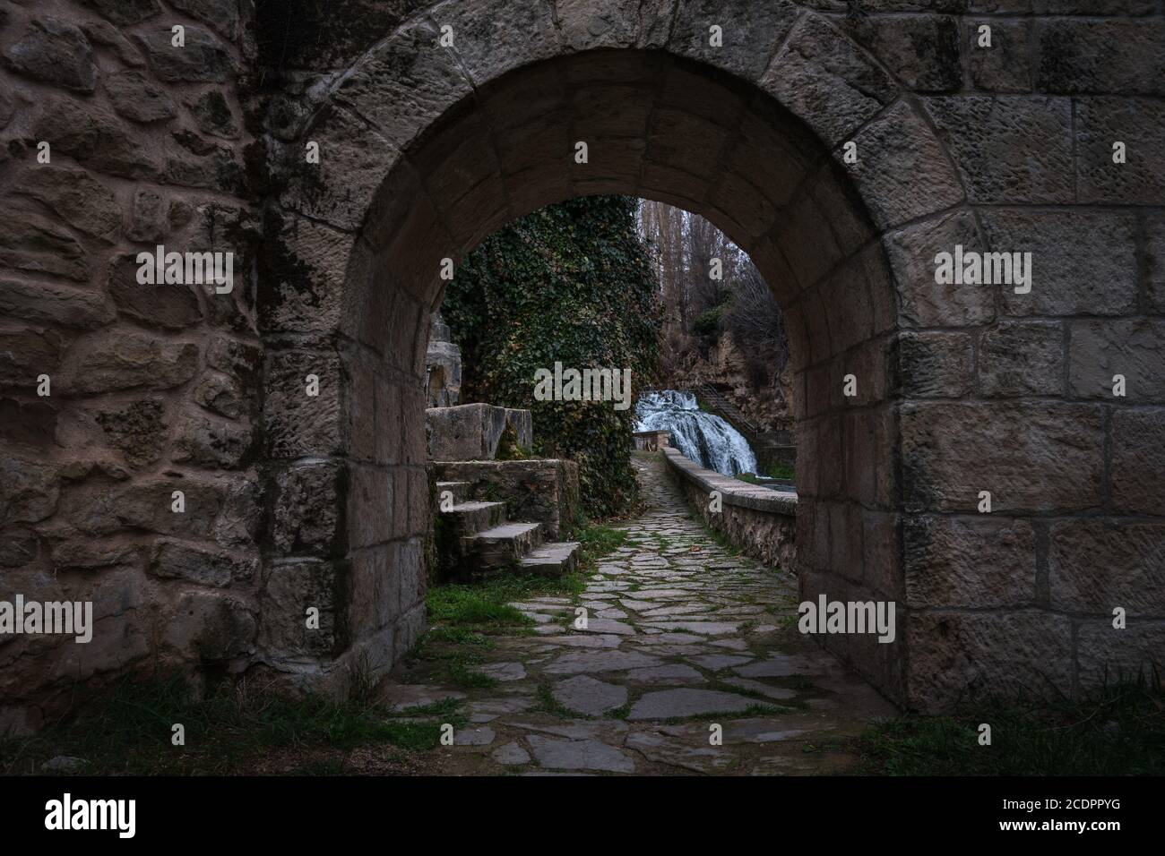 View of a waterfall through the arcade in the village of Trillo ...