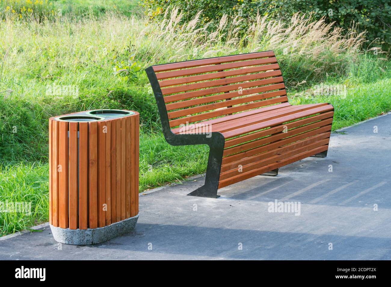 Bin for waste collection wooden bench in the city park at sunset time ...