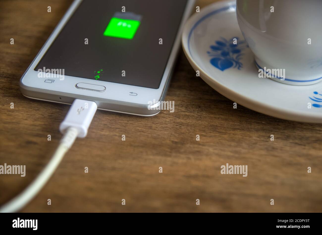 closeup of a powerbank charging a smartphone placed on a wooden table ...