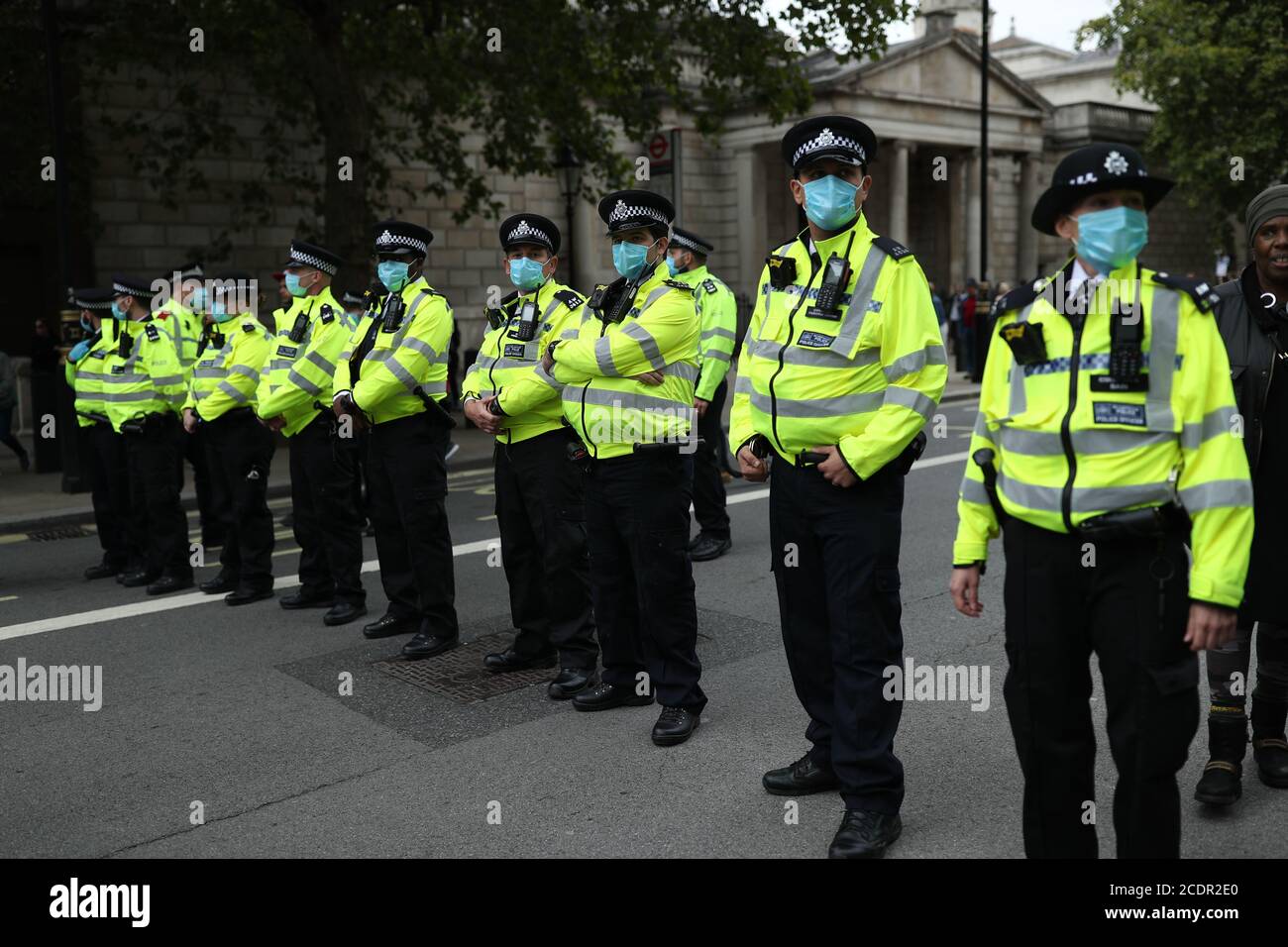 Police officers wearing face masks monitor a gathering of anti-lockdown ...