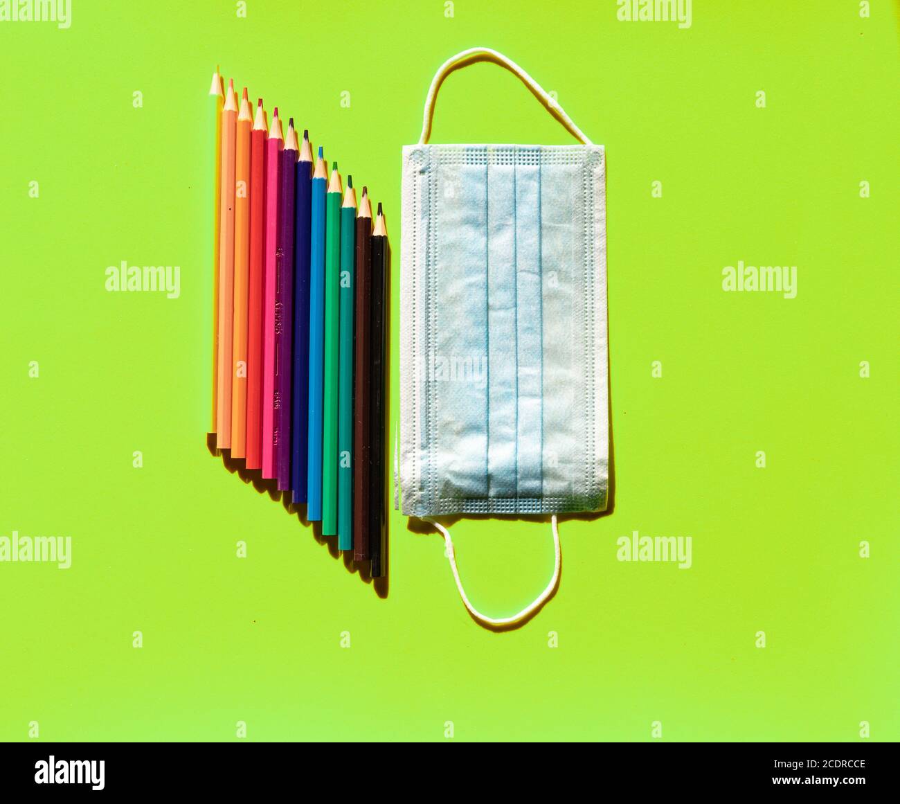 Image of colored pencils, perfectly arranged next to a hygienic mask on ...
