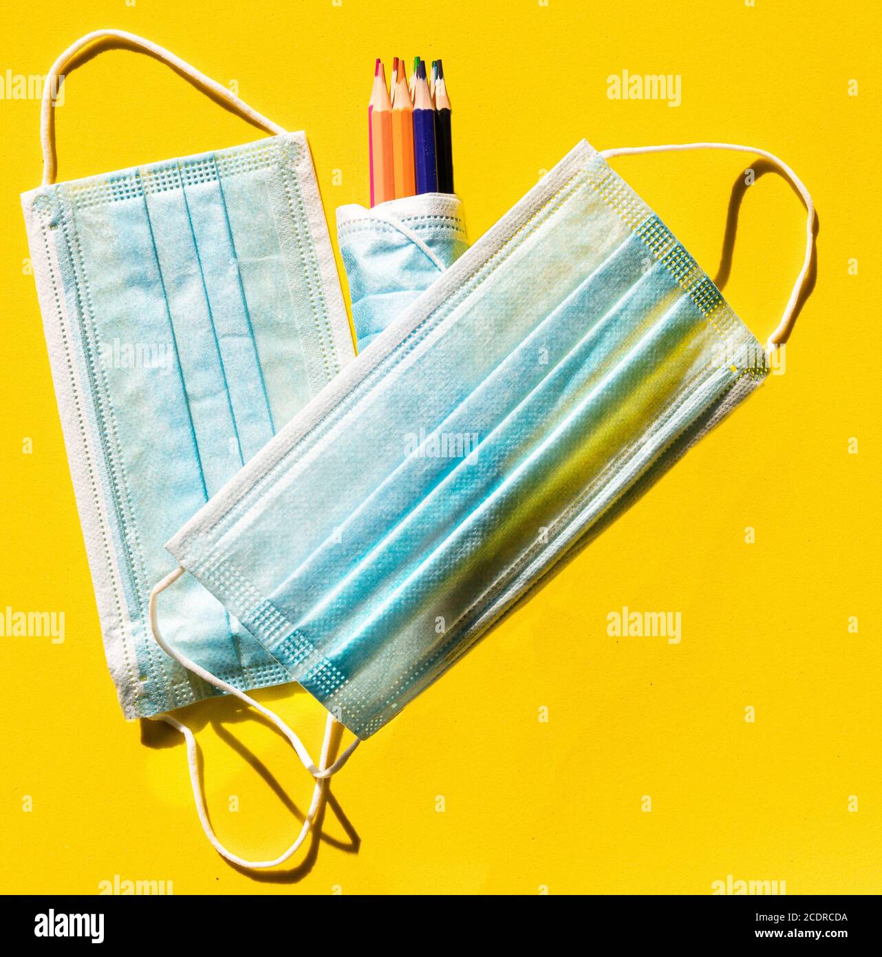 Set of colored pencils wrapped in a hygienic mask and surrounded by two ...