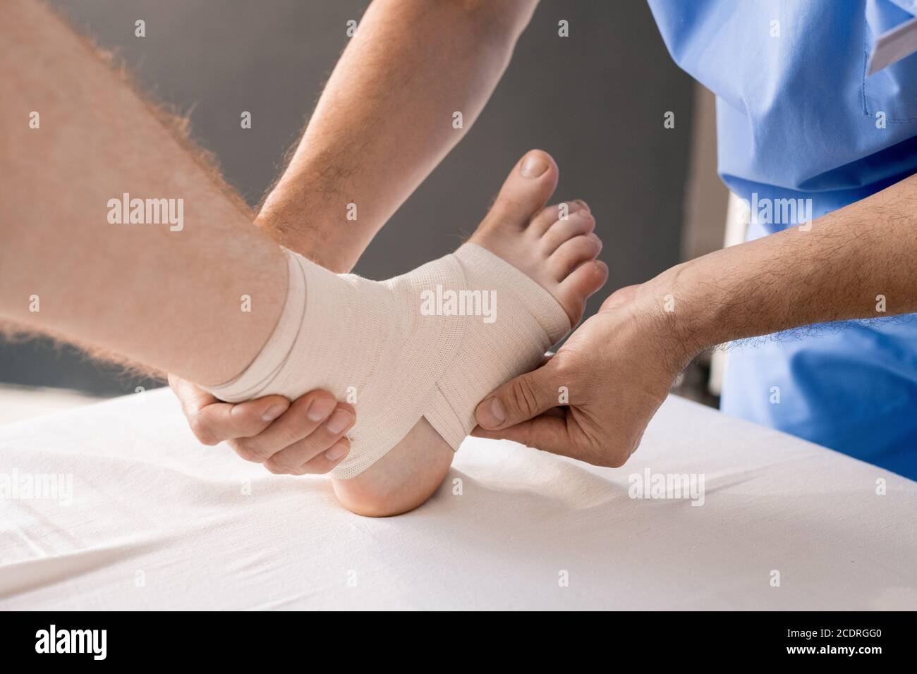 Hands of doctor wrapping foot and ankle of patient with flexible ...