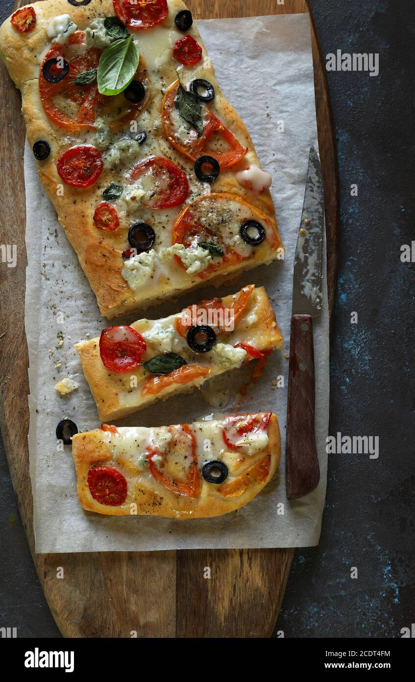 Homemade pizza with fresh vegetables, cheese and basil leaves. Top view ...