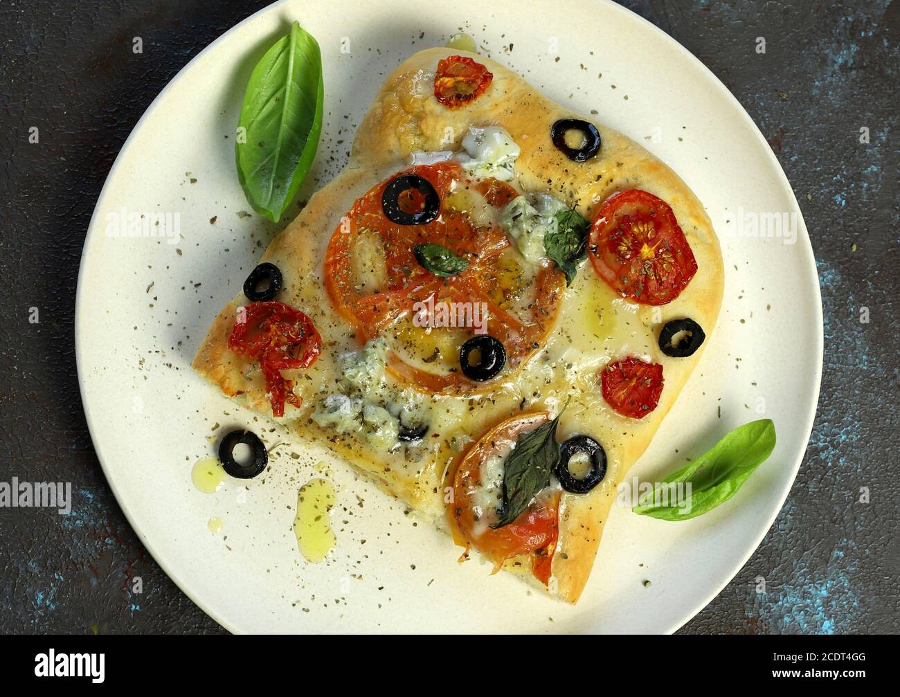 A plate with slice of pizza isolated in dark background. Top view ...