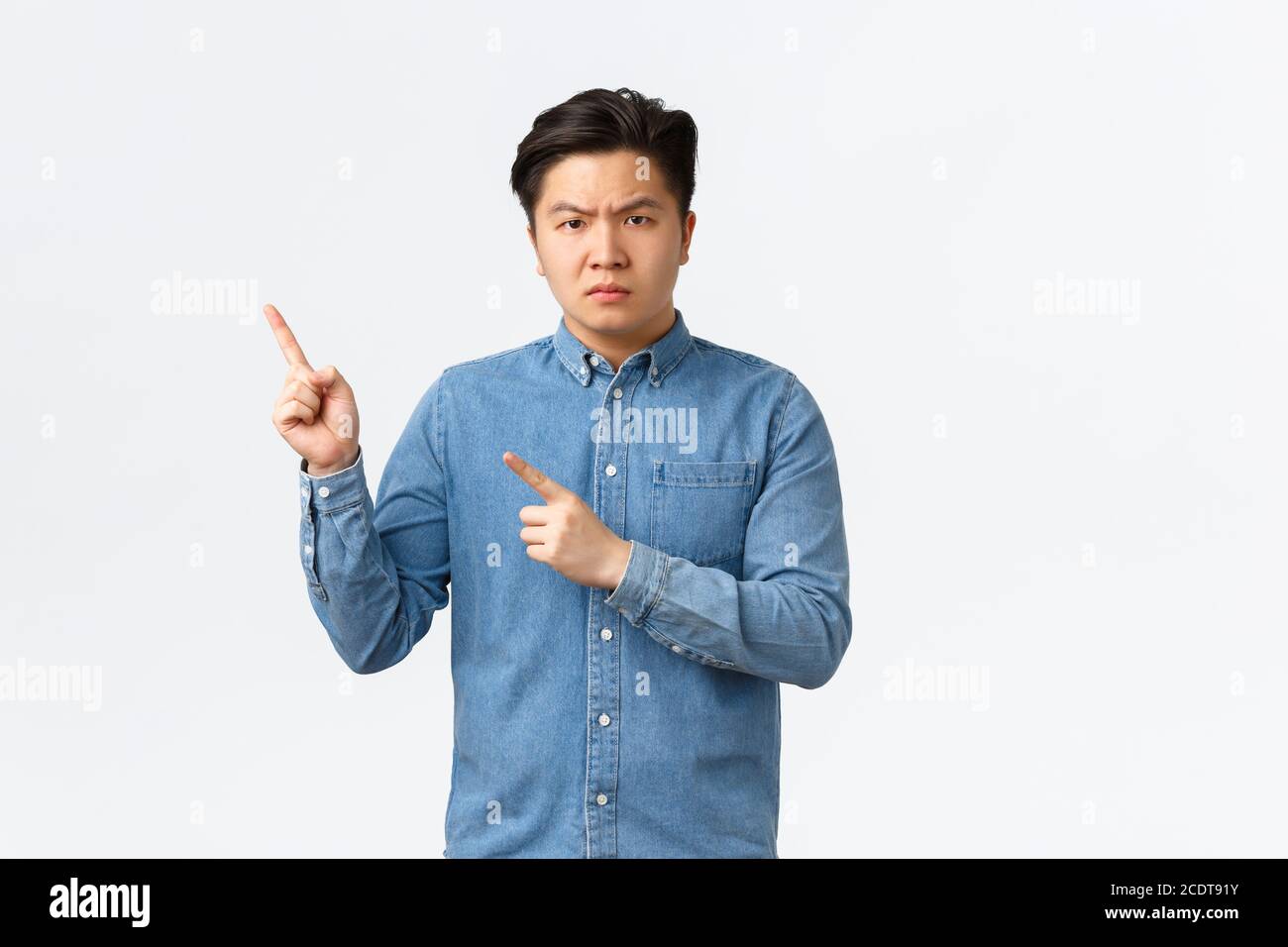 Skeptical and angry asian man pointing fingers upper left corner ...