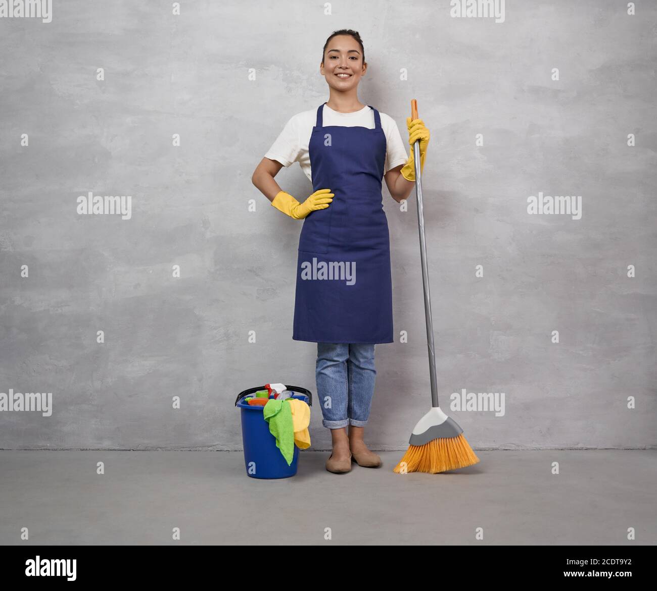 Best cleaning services. Happy young cleaning lady in uniform and rubber ...