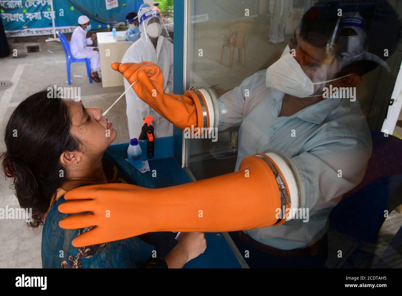 Health worker collects a nasal swab sample from a resident at Mugda ...