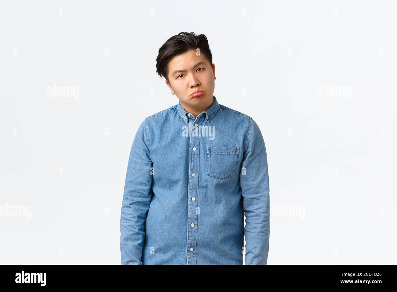 Gloomy and upset asian guy looking depressed, pouting and frowning at ...