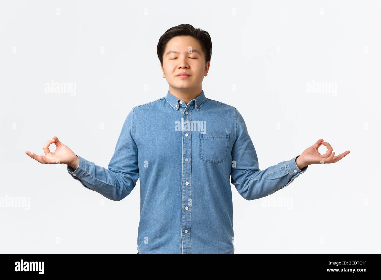 Relieved and relaxed smiling asian man with closed eyes meditating ...