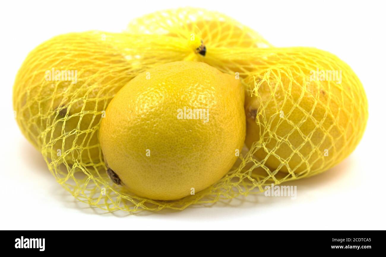 Lemons in net against white background Stock Photo - Alamy