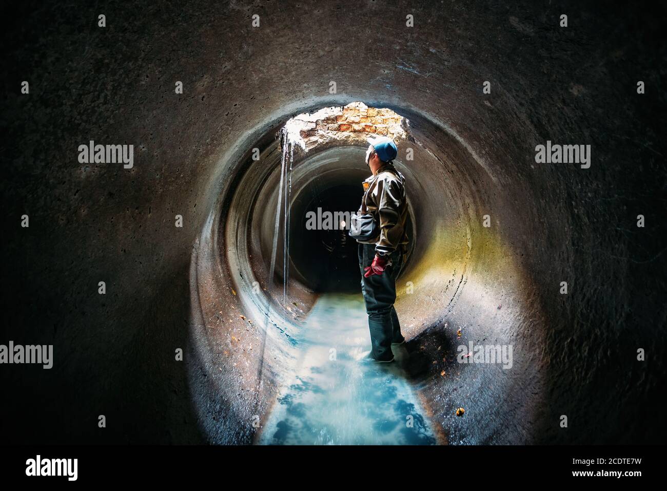 Sewer tunnel worker examines sewer system damage and wastewater leakage ...