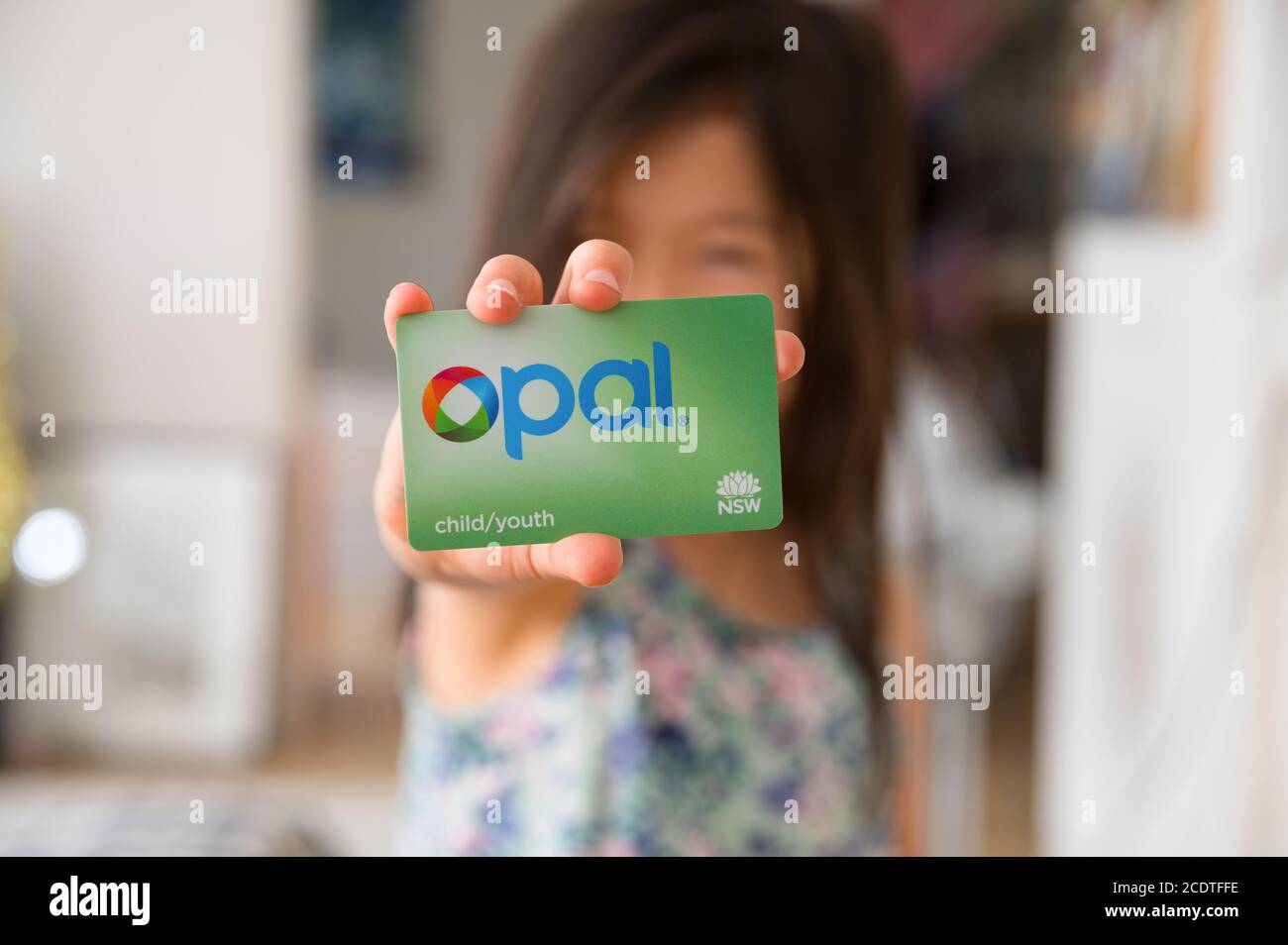Young Girl Holding a Child/Youth Opal Card and a room background blur in a sunny summer ...