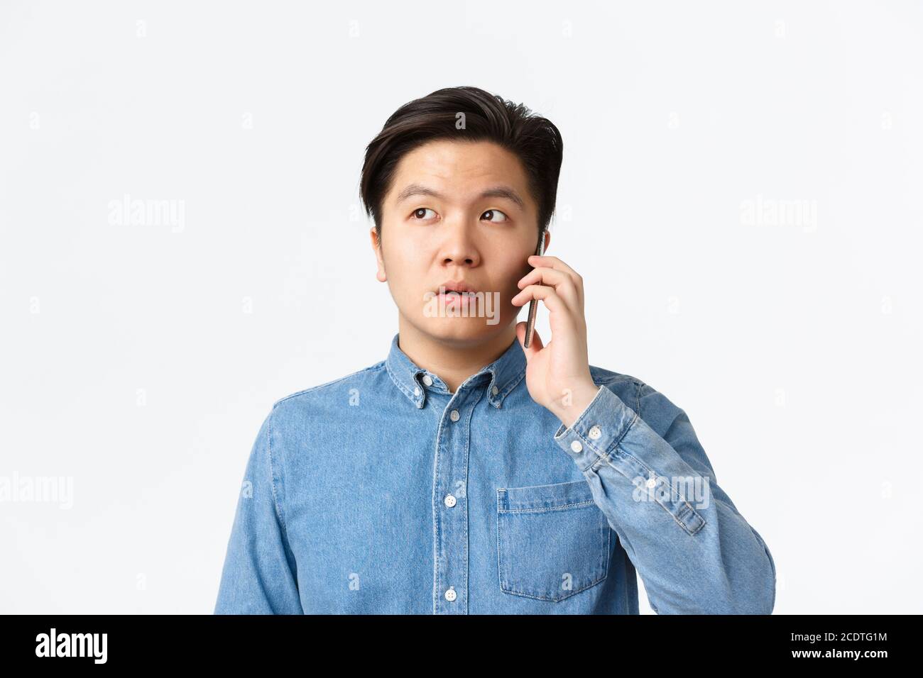 Close-up of indecisive asian guy spacing out during phone call, having ...