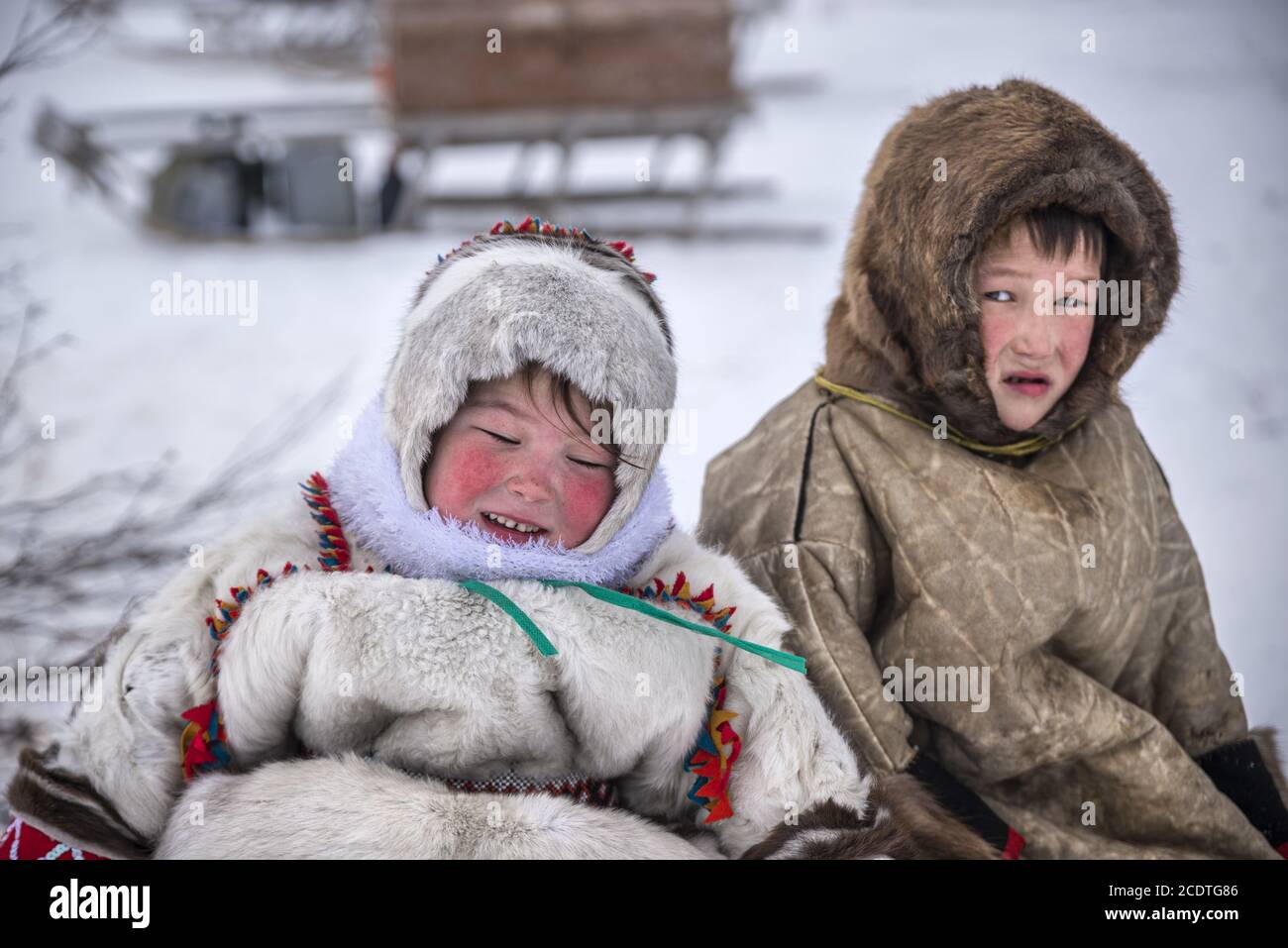 Young Nenet girl and boy sitting on a sled with traditional clothes ...