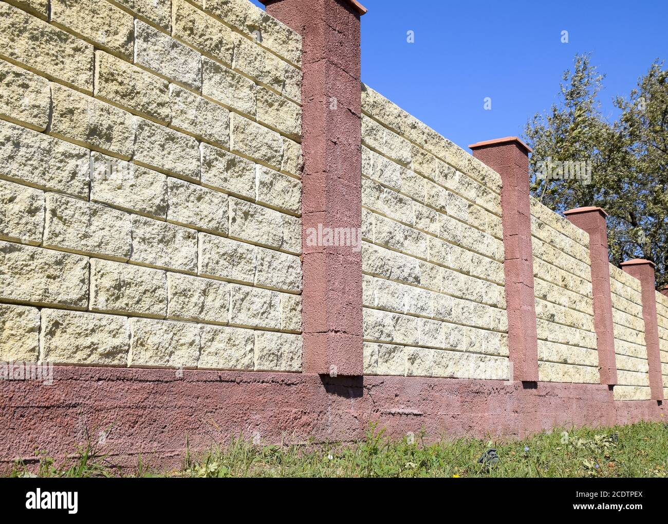 Fence made of bricks and decorative plaster. Yellow fence with red ...