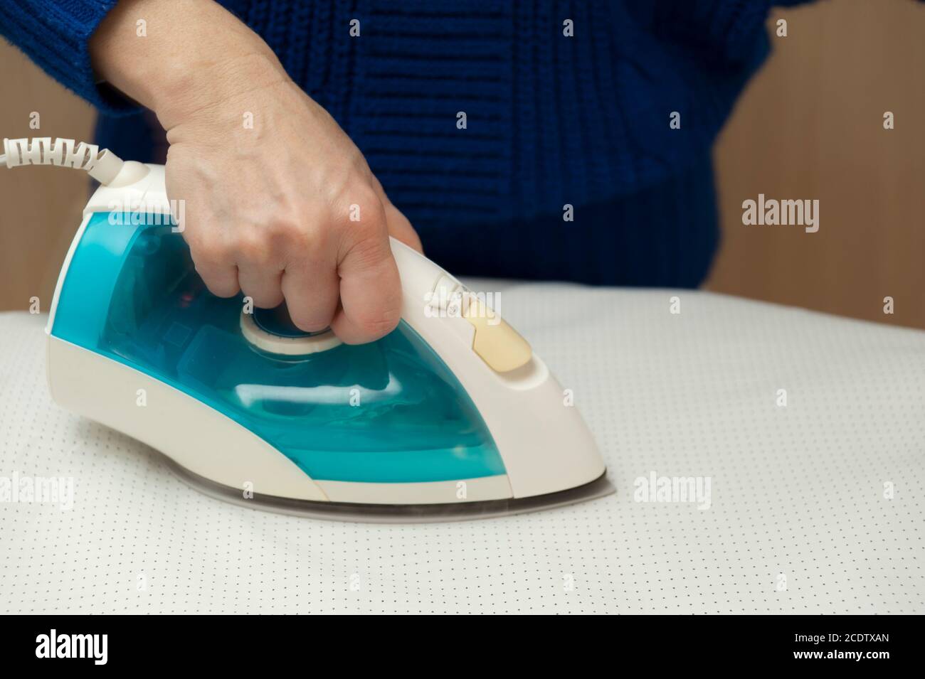 Woman ironing white clothes on ironing board. Close-up. Horizontal shot ...
