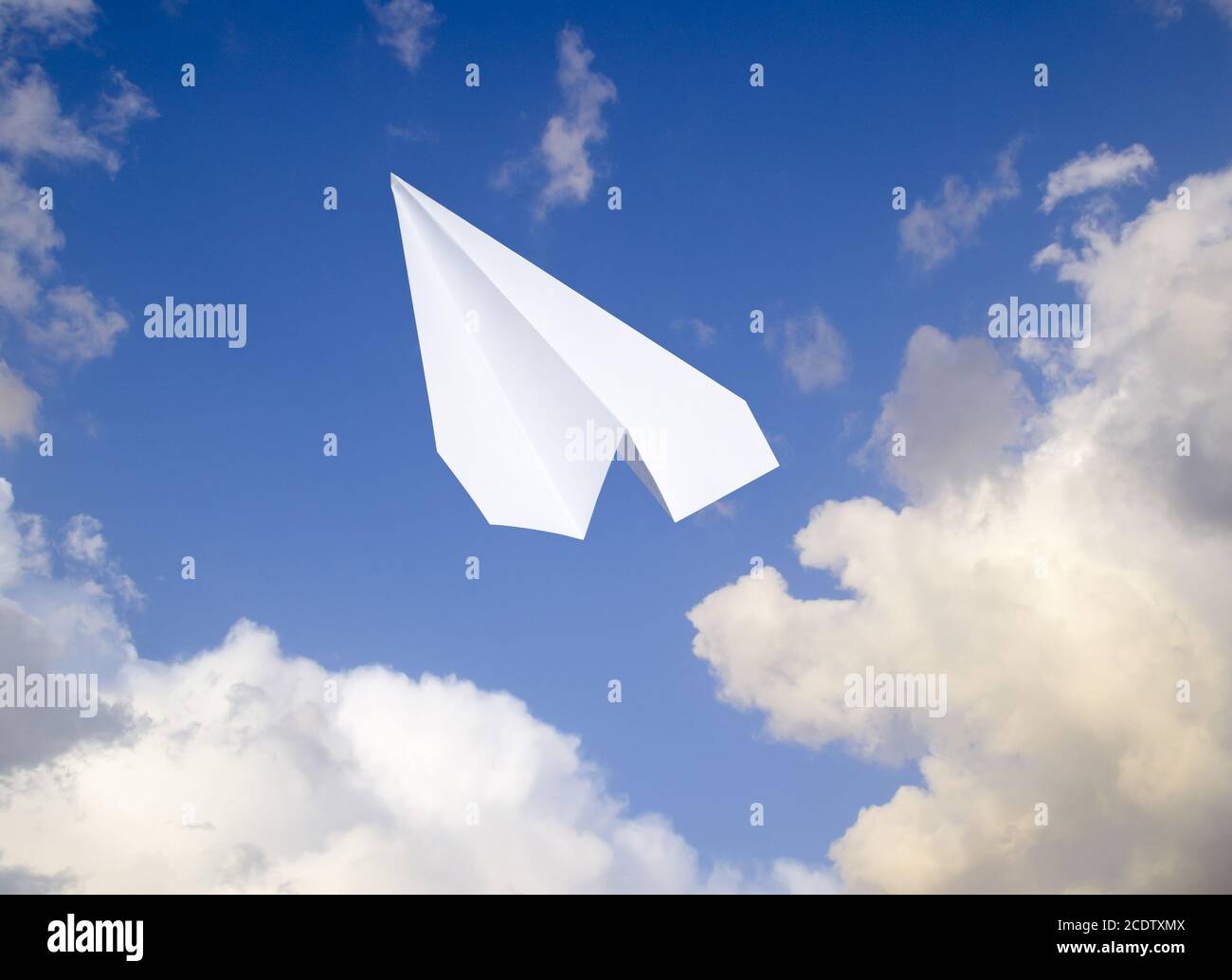 White paper airplane in a blue sky with clouds. The message symbol in ...