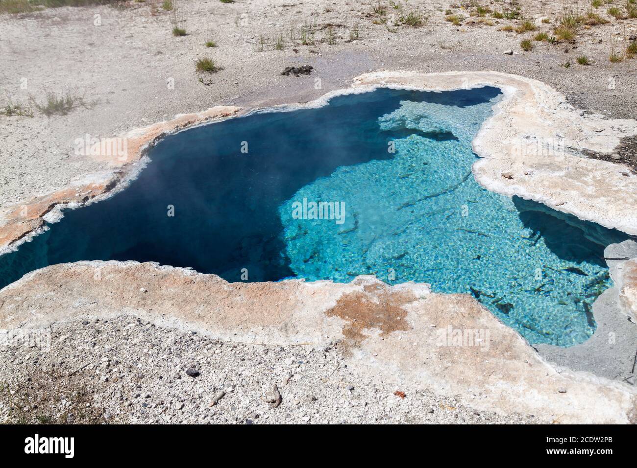 A deep blue geothermal pool of steaming water rimmed by a crust of ...