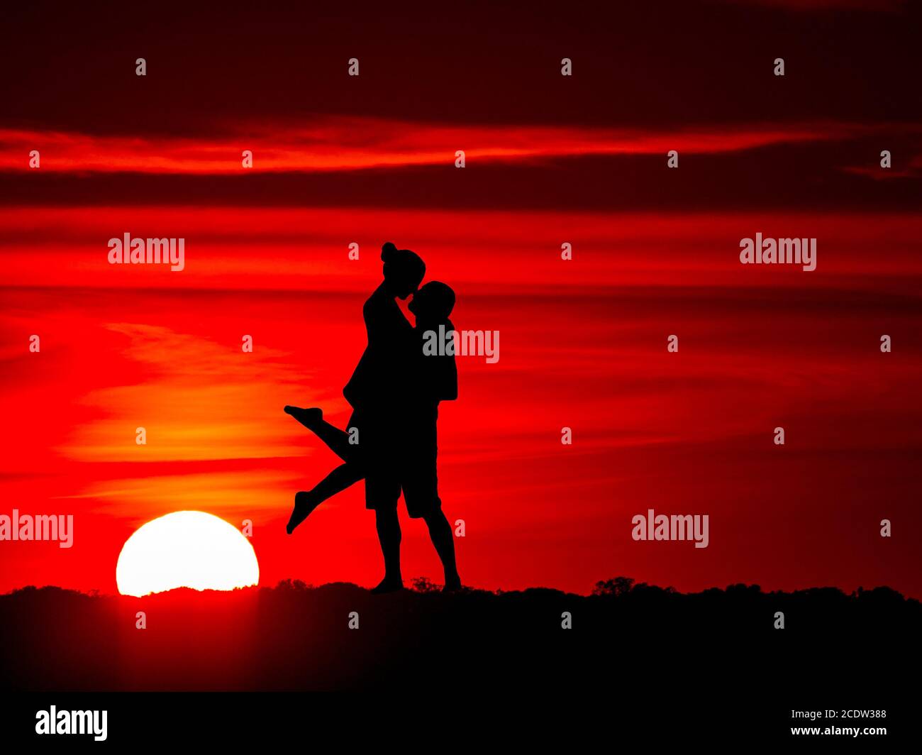 Romantic couple on countryside at the sunset with the sun and red sky ...