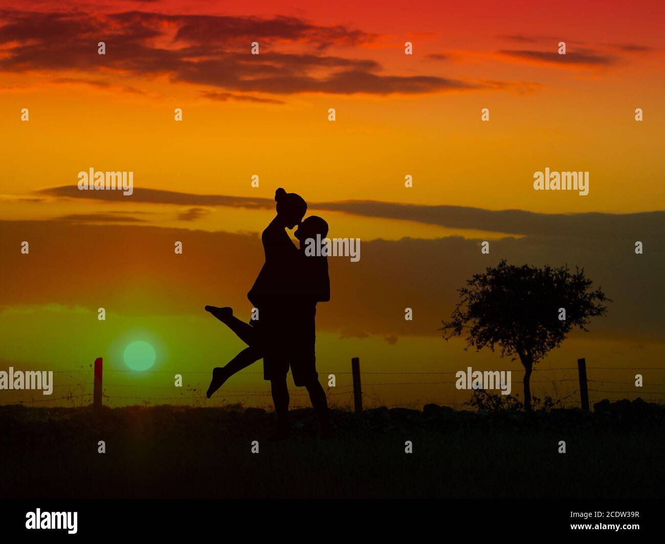 Romantic couple on countryside at the sunset with the sun and one tree ...