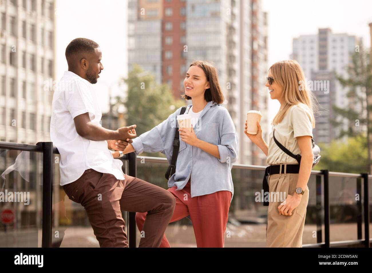 Happy young blond and brunette women having drinks while talking to ...