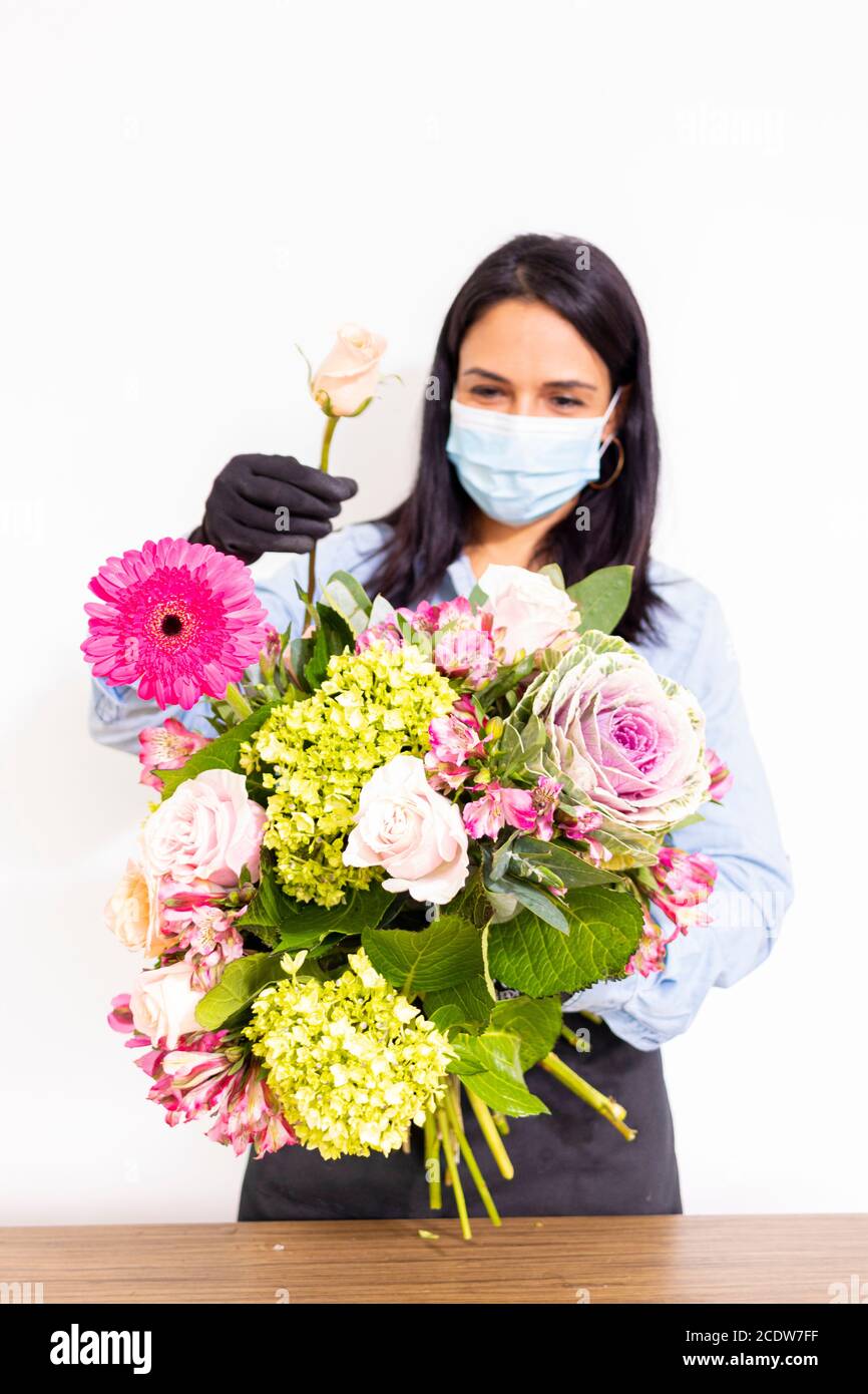 Cute woman florist is making a bouquet of roses, hydrangeas and ...