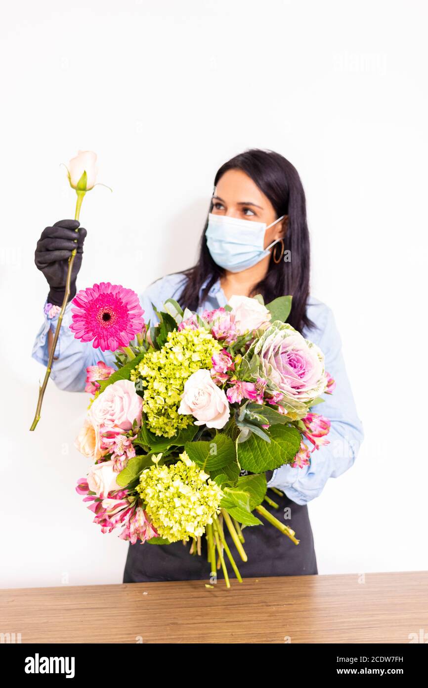 Cute woman florist is making a bouquet of roses, hydrangeas and ...