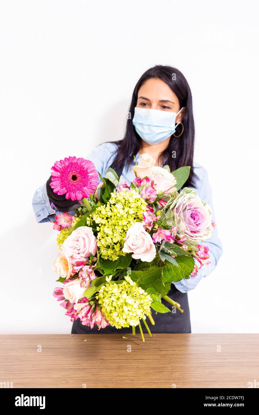 Cute woman florist is making a bouquet of roses, hydrangeas and ...