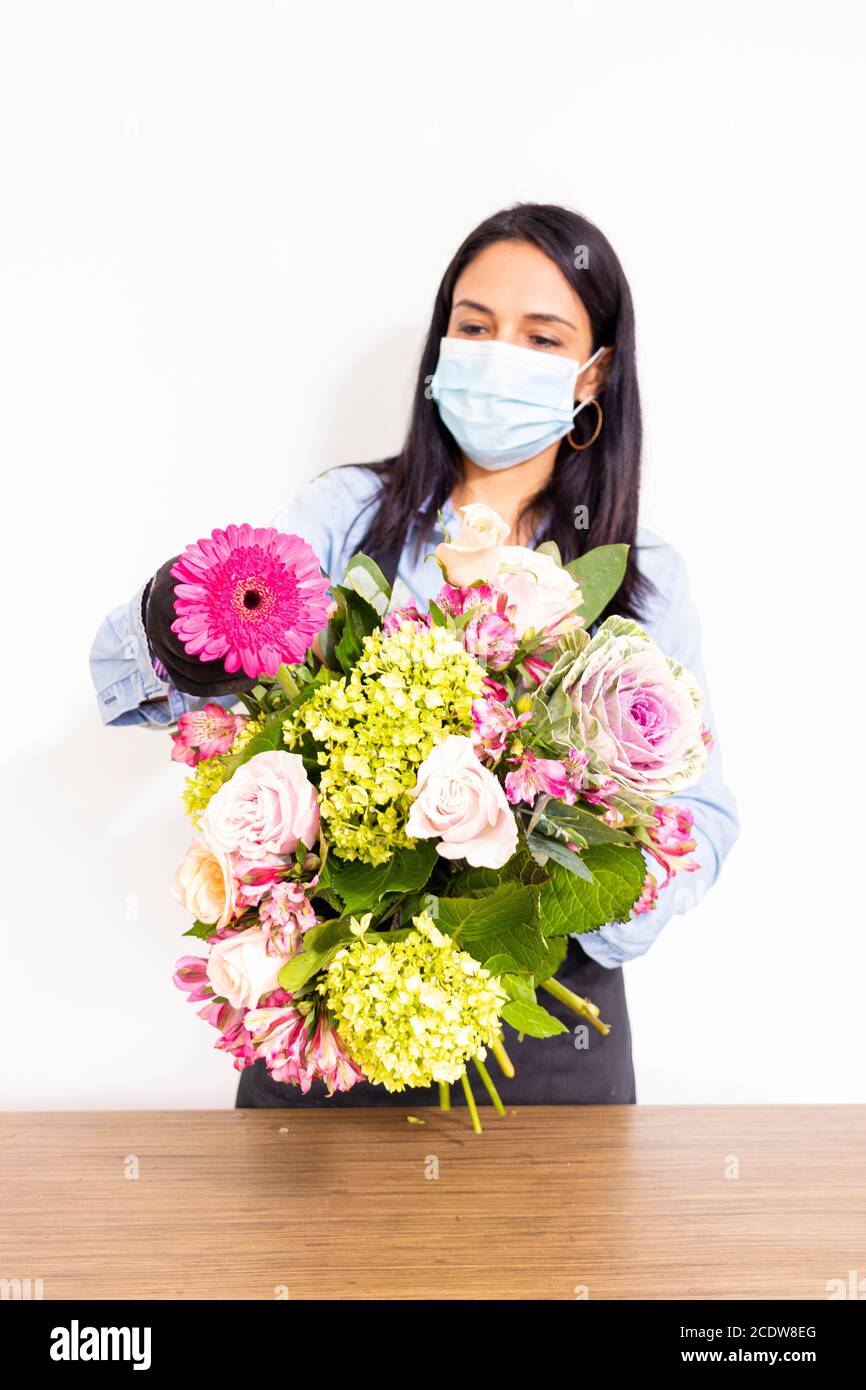 Cute woman florist is making a bouquet of roses, hydrangeas and ...