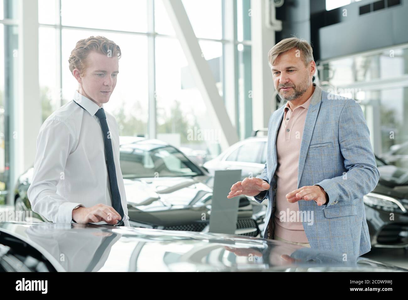 Mature male consumer in casualwear standing by one of new luxurious ...