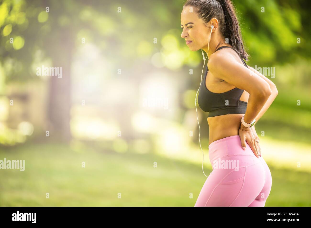 Back pain during sports. Young woman with an athletic figure and a ...