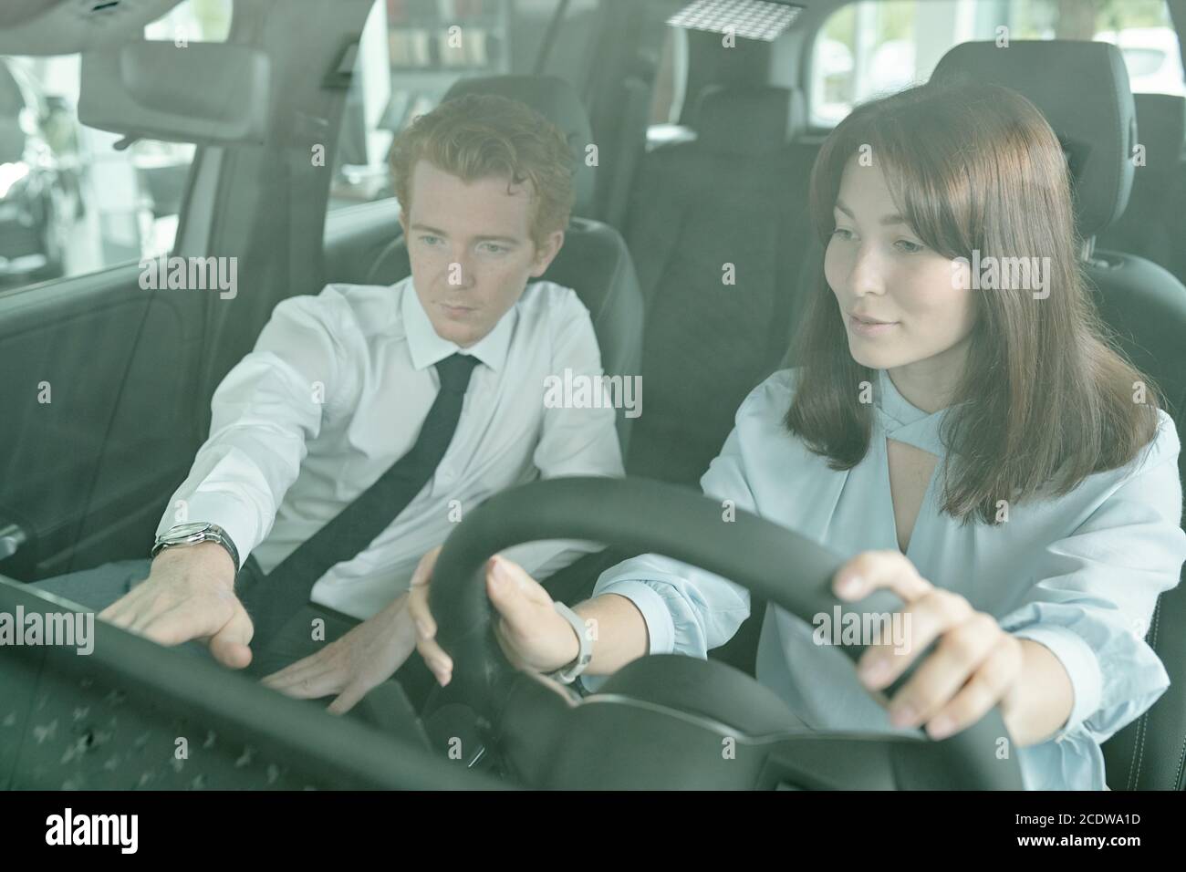 Young pretty brunette woman sitting in new car during test drive with ...