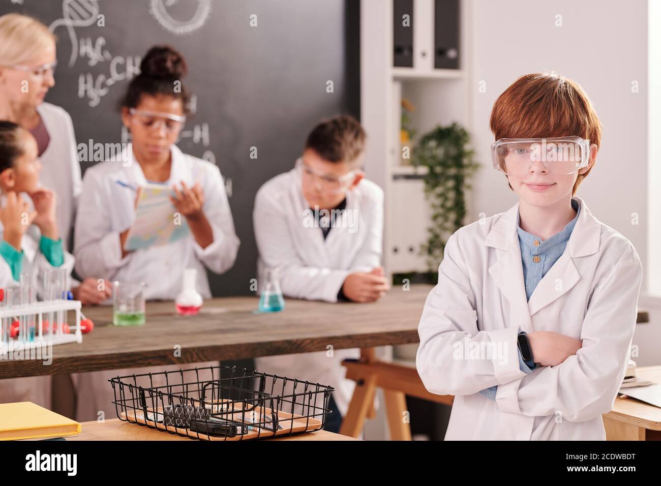 Happy pupil of secondary school in whitecoat and protective eyeglasses ...